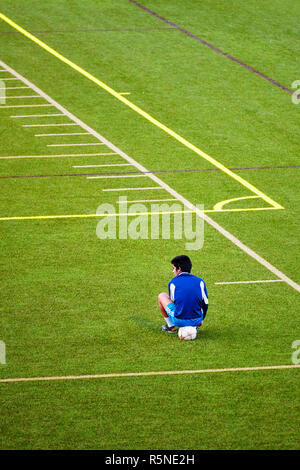 Unhappy boy sitting on a football. Lost a game concept Stock Photo - Alamy