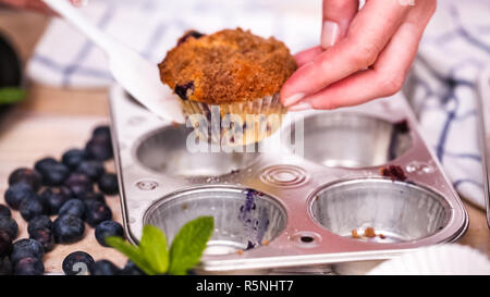 Taking blueberry muffins out of metal muffin pan Stock Photo - Alamy