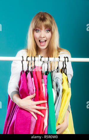 Pretty woman grabbing clothing in wardrobe. Young undecided shopper ...