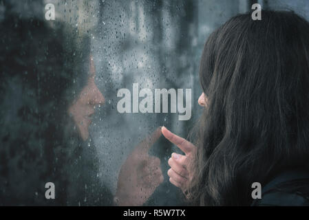 Young woman touching rainy window Stock Photo - Alamy
