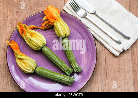 plate of courgettes with their flower on a wood table Stock Photo - Alamy