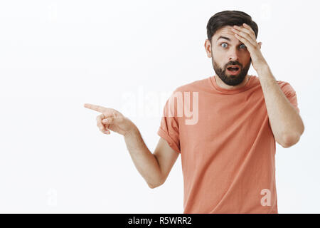 Shocked man cannot pull himself together standing impressed and worried ...