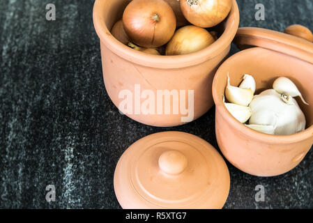 clay jars with onions and garlic on a black granite table top ready for ...