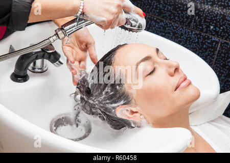 Hair wash procedure in a beauty salon. A hair dresser is washing her ...