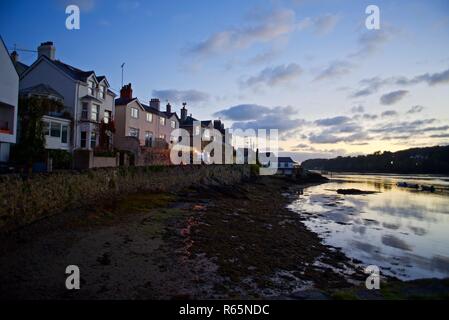 House on the banks of the Menai Strait with Menai suspension bridge in ...