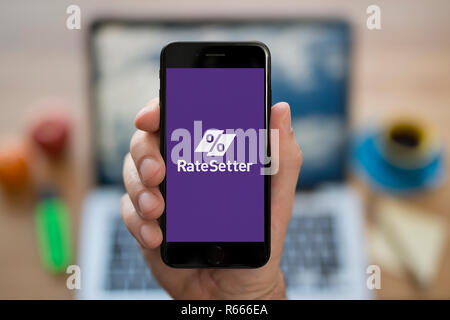 A man looks at his iPhone which displays the RateSetter logo (Editorial ...