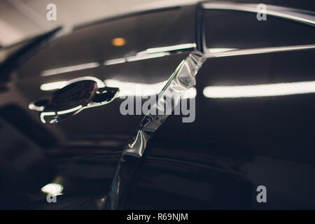 Worker hands installs car paint protection film wrap Stock Photo - Alamy
