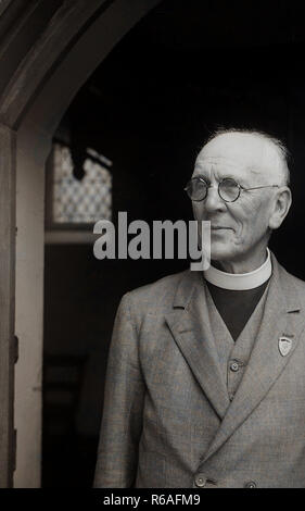 1950s, historical, an elderly Parish priest standing at the entrance to ...