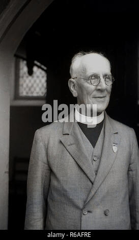 1950s, historical, an elderly Parish priest standing at the entrance to ...