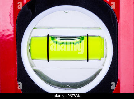 Red spirit level with a green bubble indicator is situated horizontally ...