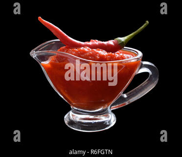 Red chili sauce in a black bowl surrounded by fresh red chillies ...