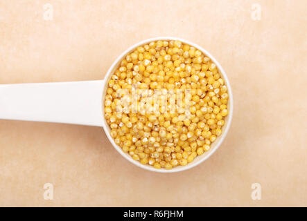 Raw millet in measuring spoon on brown background Stock Photo - Alamy