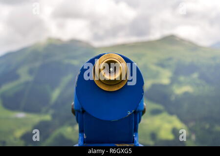 Public telescope arrayed against mountain range Alps in Austria, cloudy ...