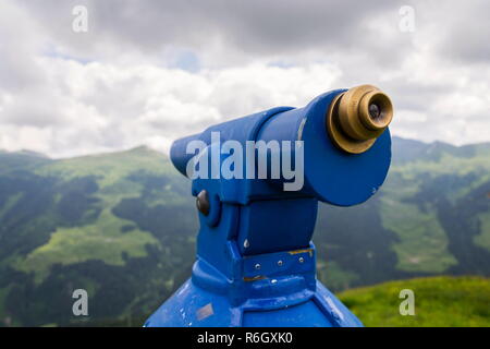 Public telescope arrayed against mountain range Alps in Austria, cloudy ...