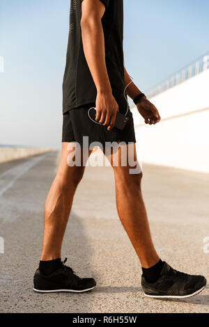 Cropped photo of a young guy sportsman outdoors on the beach holding ...