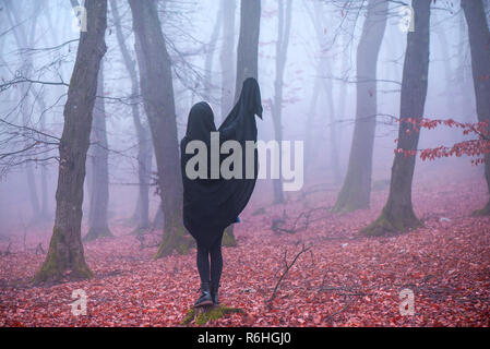 Girl in black hood running away from danger deep in dark forest. Thick ...