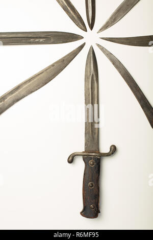 Isolated old dagger with assorted blades of weapons all pointing to a ...