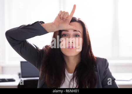 Portrait Of A Young Businesswoman Showing Loser Sign Stock Photo - Alamy
