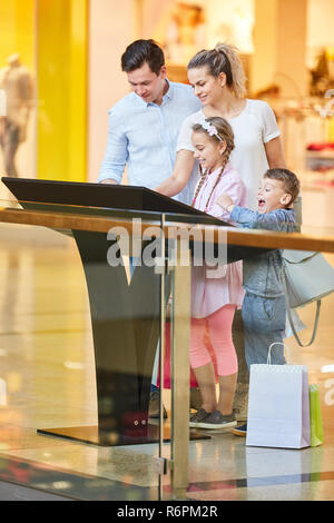 Family at the information kiosk in the mall as an interactive customer ...