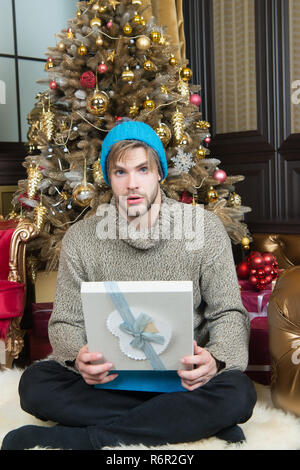 Boxing day concept. Macho in santa hat with present on white brick wall ...