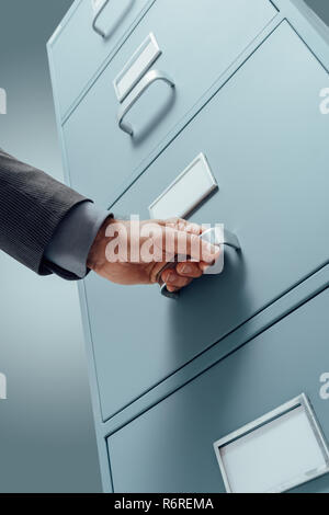 Office clerk searching for files in the filing cabinet, he finds a ...