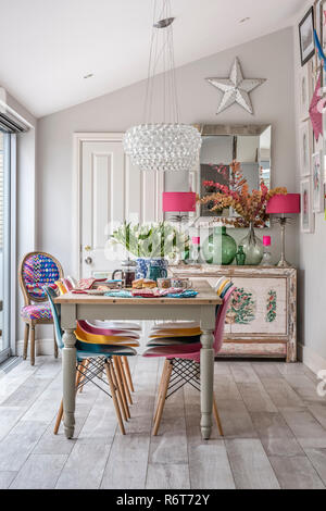 Caboche pendant above table with multicoloured Eames-style chairs Stock ...