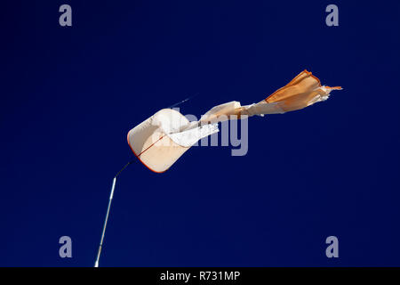torn windsock against dark blue sky, storm aftermath background Stock ...