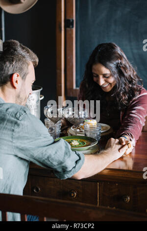 A couple holding hands across a table Stock Photo - Alamy