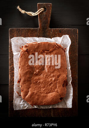 baked rectangular chocolate brownie pie is cut into squares, a wooden ...
