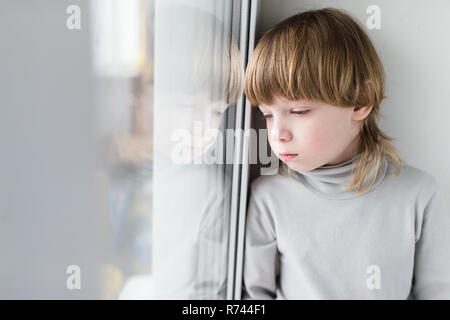 Sad child sitting on window shield and looking out the window Stock ...