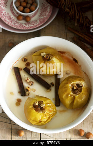 Baked apples with raisins, hazelnuts and cinnamon on wooden background ...