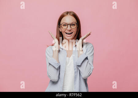 Emotional woman in glasses and in a striped T-shirt gestures with her ...