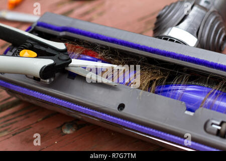 close up of the under side of a vacuum cleaner with har wrapped around ...