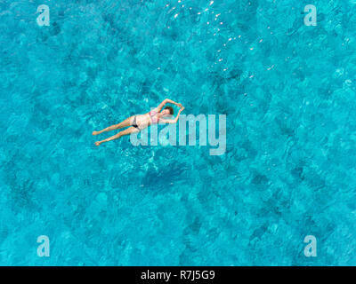 Aerial view of pregnant woman floating on her back in transparent sea ...