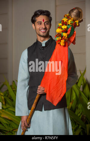 Smiling maharashtrian man in traditional dress holding the gudi while ...