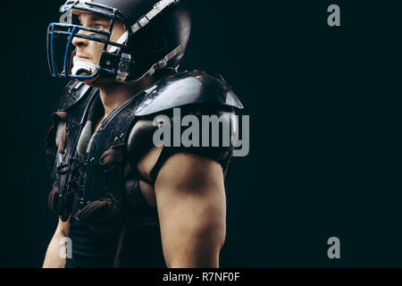 Football player wearing protective gear and holding helmet Stock Photo ...