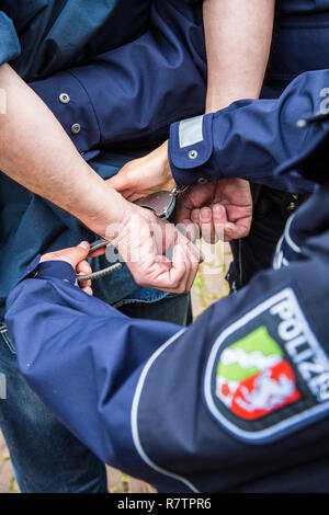 Police officer putting handcuffs on prisoner in orange jumpsuit ...