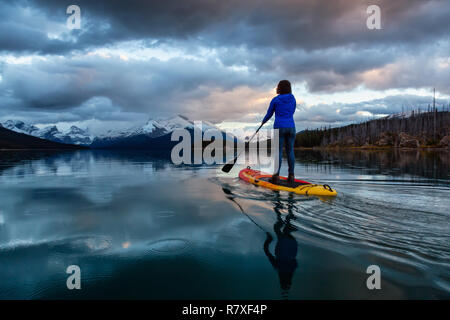 Girl Paddle Boarding in a peaceful and calm glacier lake during a ...