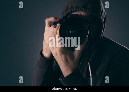 Hooded photographer behind DSLR camera, low key portrait Stock Photo ...