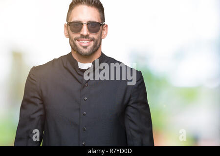 Young Christian priest wearing sunglasses over isolated background ...