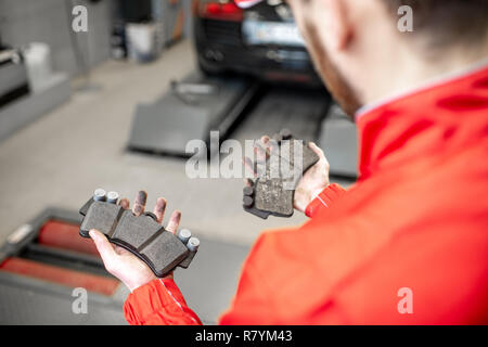 Auto mechanic holding new brake pad at the car service, close-up view ...
