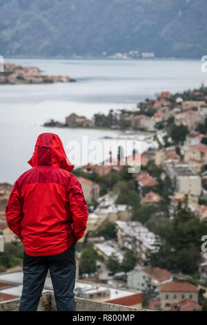 Man dressed in a red waterproof jacket standing on a lookout and ...
