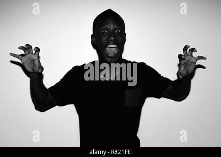 Spooky horror portrait of young African man thinking in black and white ...