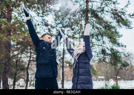 Winter activities. Couple throwing snow up in winter forest. People ...
