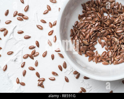 Flax seeds with copy space. Brown flax seed on white concrete textured background. Top view or ...