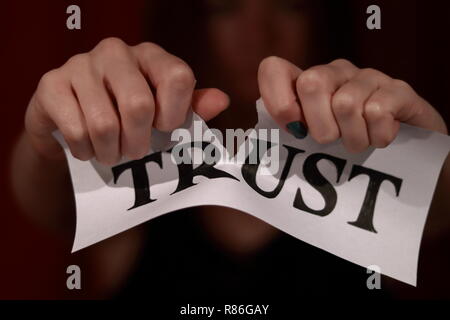 Ripped white paper with drawn letters of "TRUST" on it. Girl ripping ...