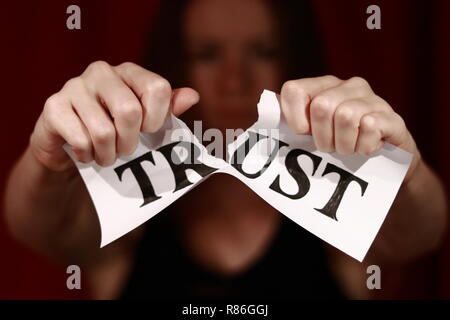 Ripped white paper with drawn letters of "TRUST" on it. Girl ripping ...
