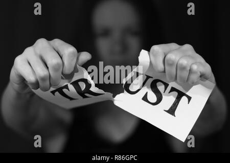 Ripped white paper with drawn letters of "TRUST" on it. Girl ripping ...
