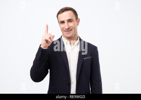 Satisfied young man showing index fingers up, giving advice or ...