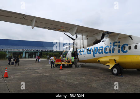 Baggage handlers unload luggage from a Cebu Pacific ATR 72-500 aircraft ...
